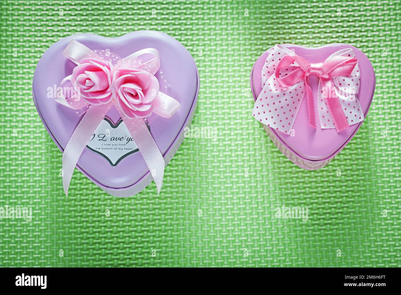 Metal pink heart-shaped present boxes on green background celebrations ...