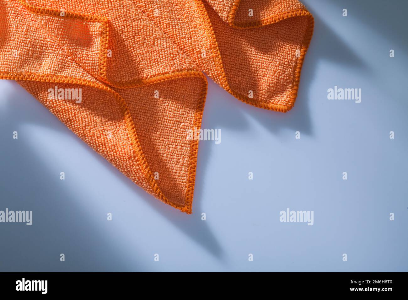 Orange kitchen dishwashing rag on white surface Stock Photo - Alamy