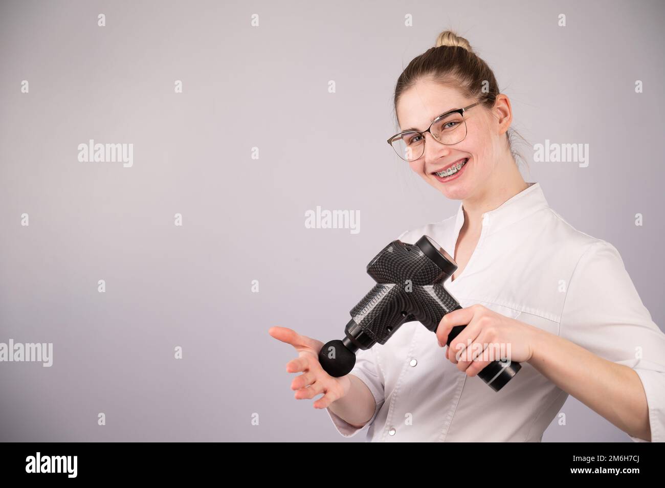 The masseur doctor holds a masseur gun on a white background Stock ...