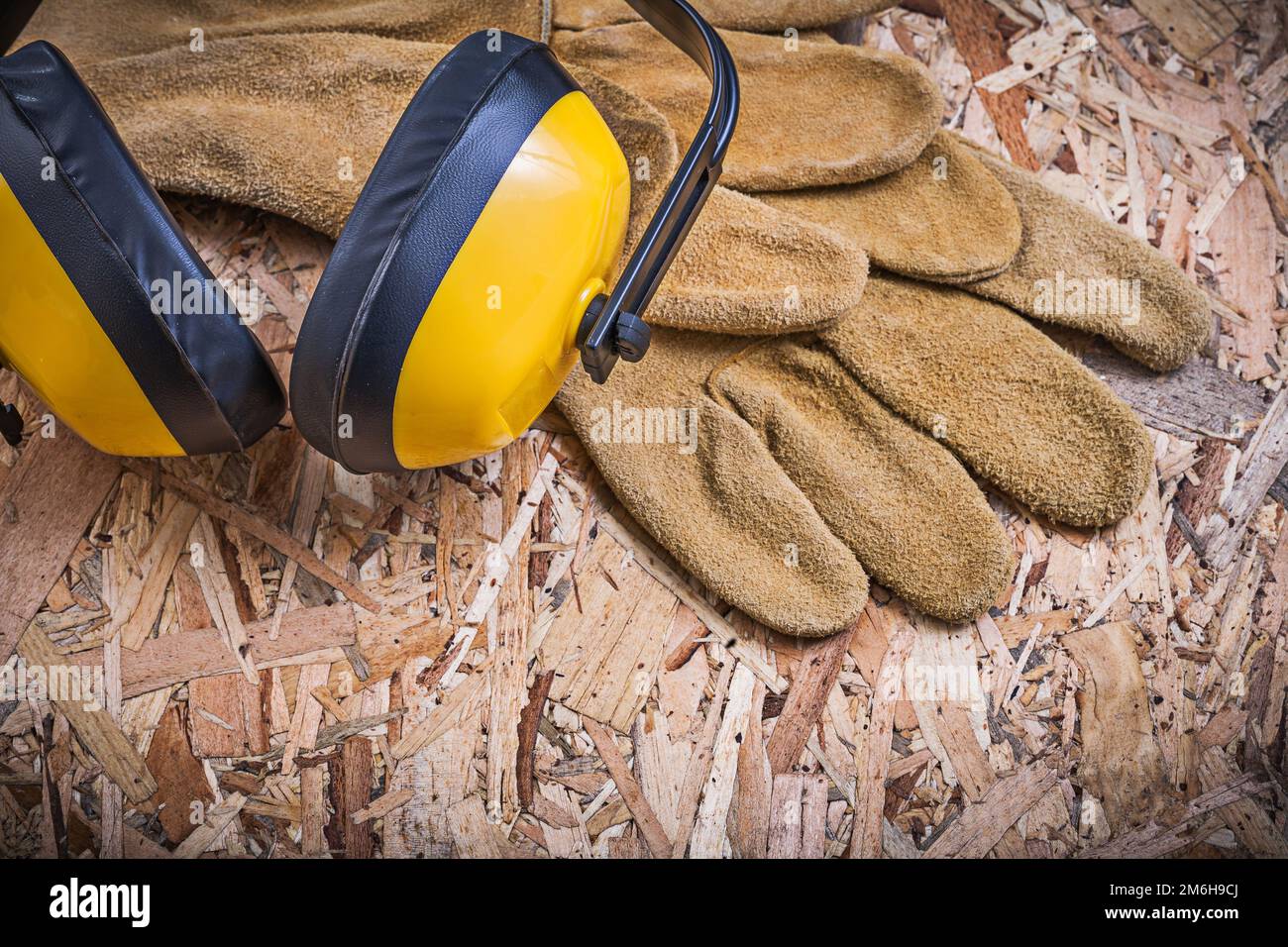 Safety leather gloves ear muffs on OSB Stock Photo - Alamy