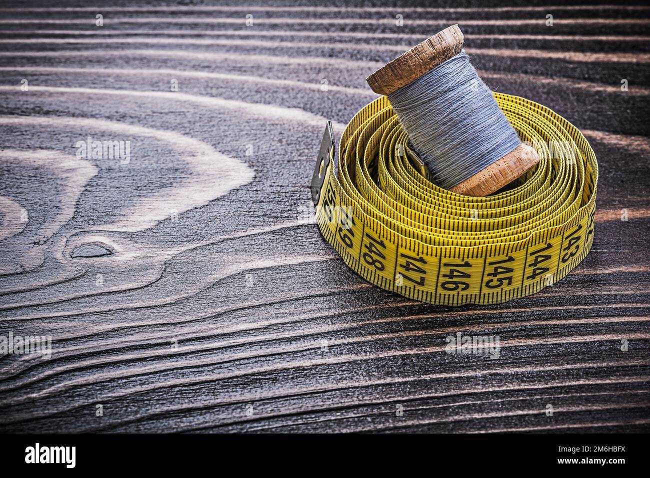 Vintage spool of thread tape measure on wooden board handicraft concept ...