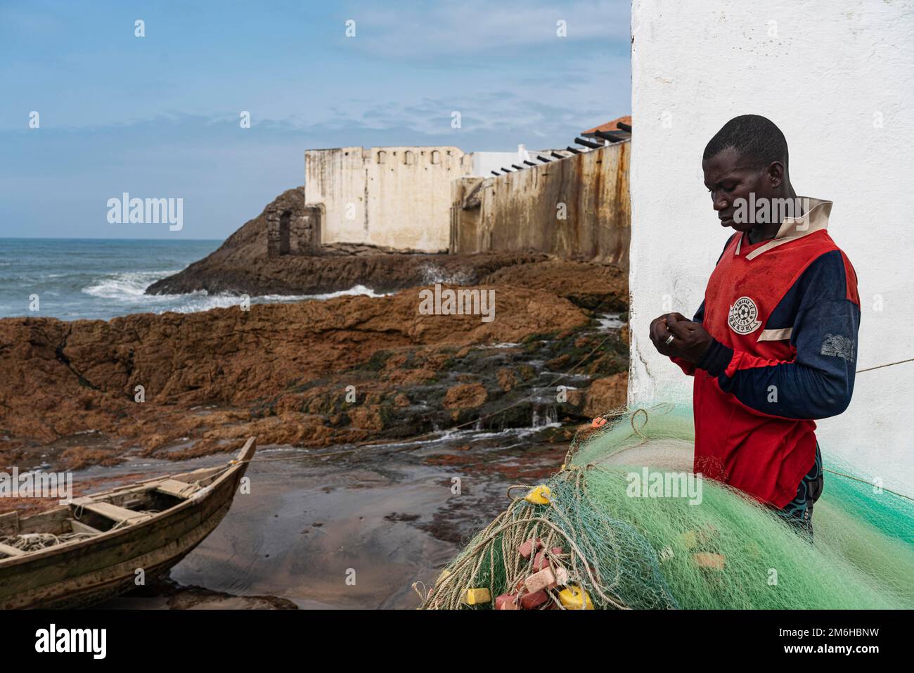 Fisherman mending net, fishing boat, behind Cape Coast Castle, Slave ...