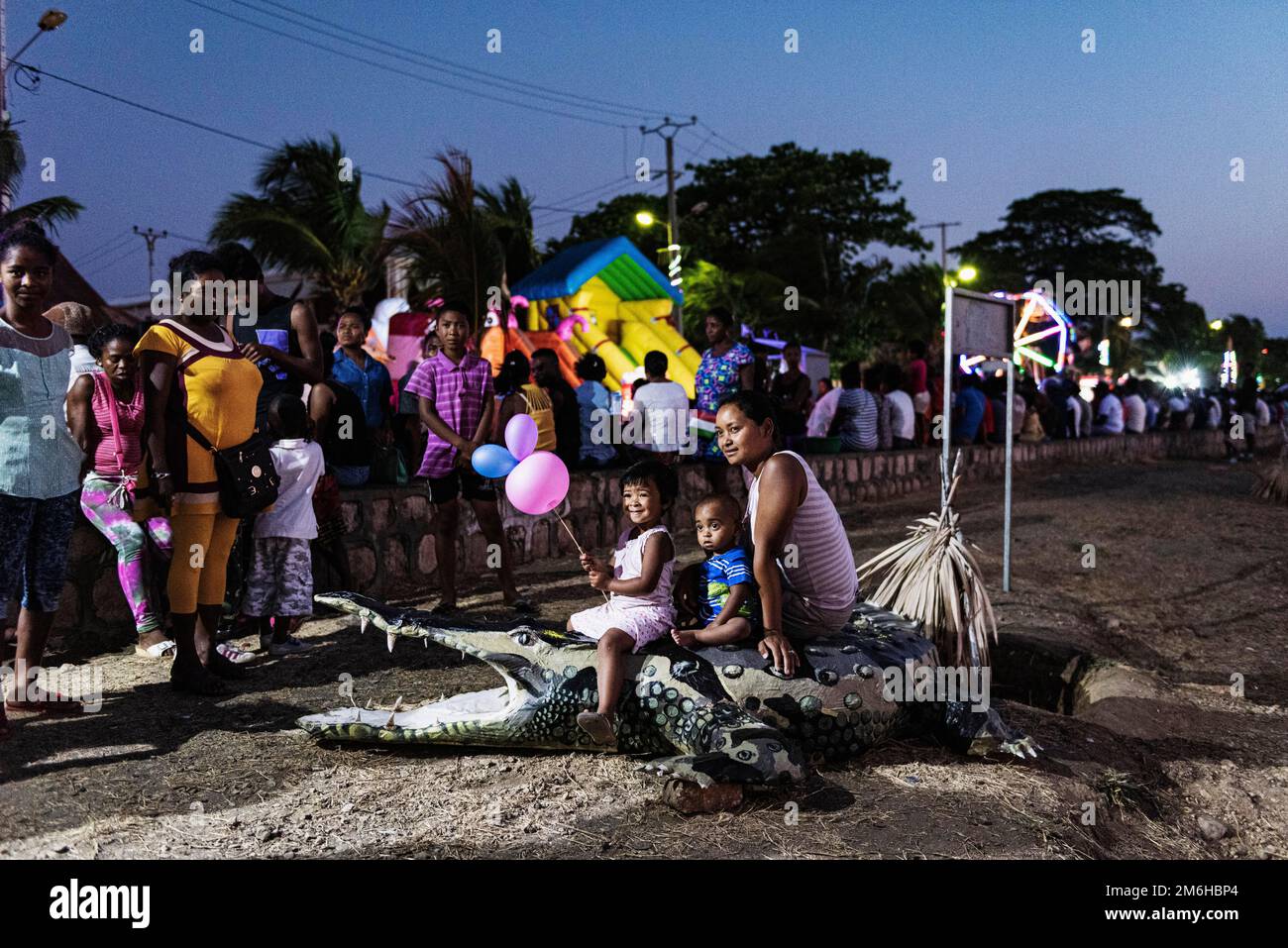 Mother and two children posing on artificial crocodile, dummy, papier ...