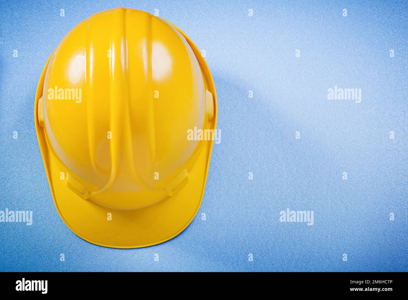 Yellow building helmet on blue surface construction concept Stock Photo ...