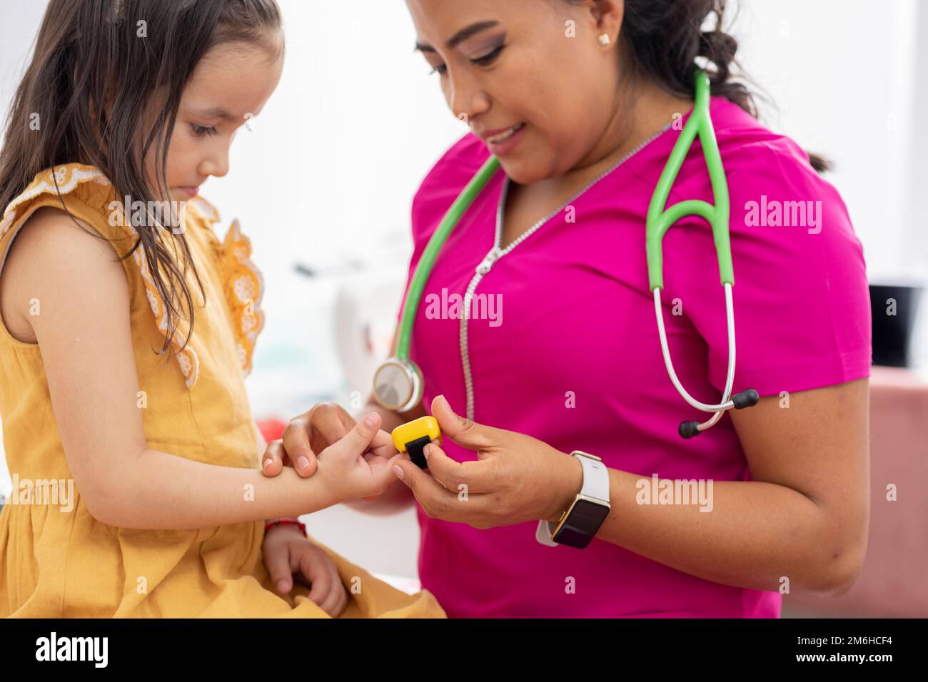 Latina pediatrician doctor checks a girl with an oximeter in her office ...