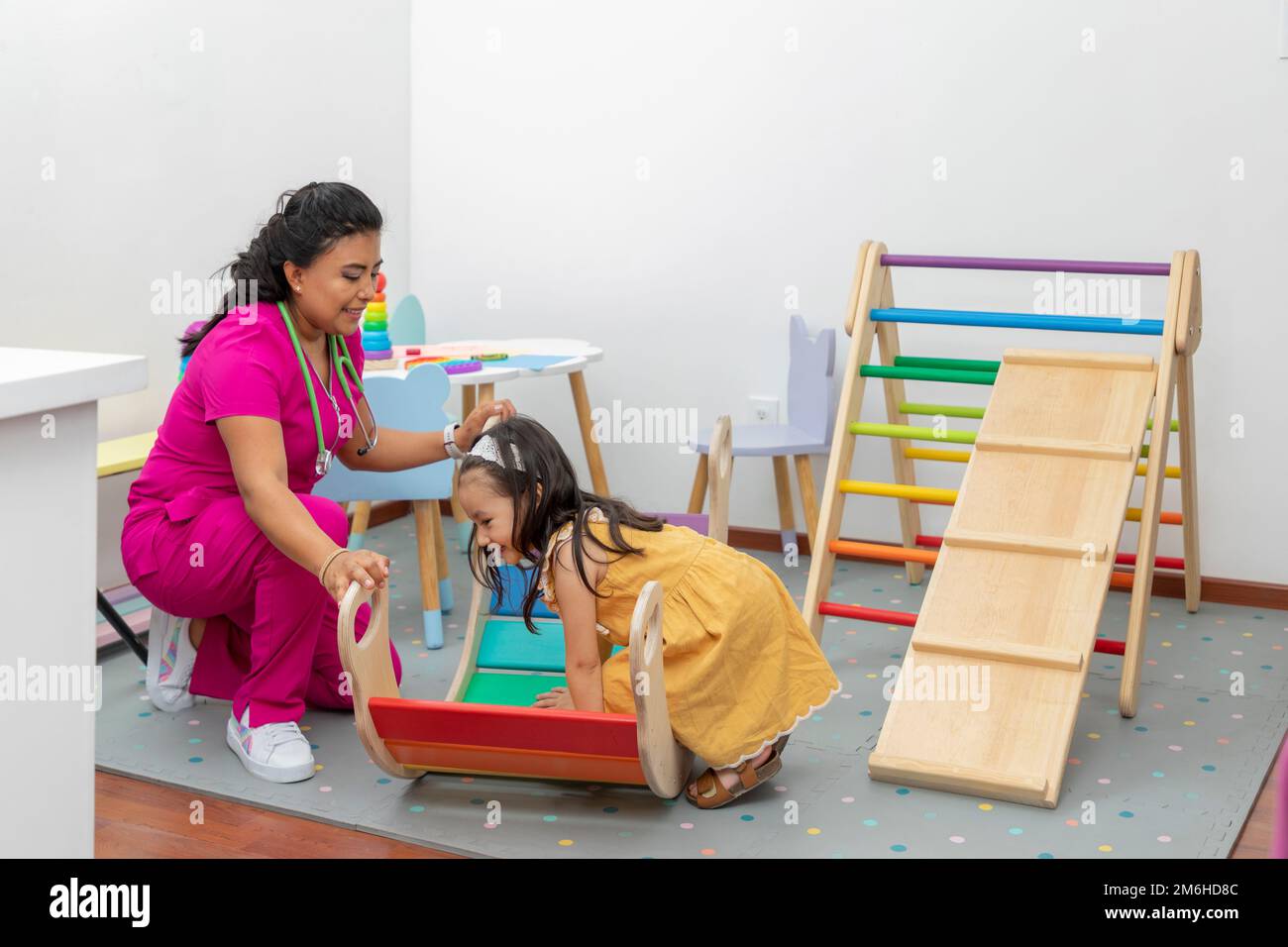 Pediatric doctor with a girl playing in the recreational area of her ...