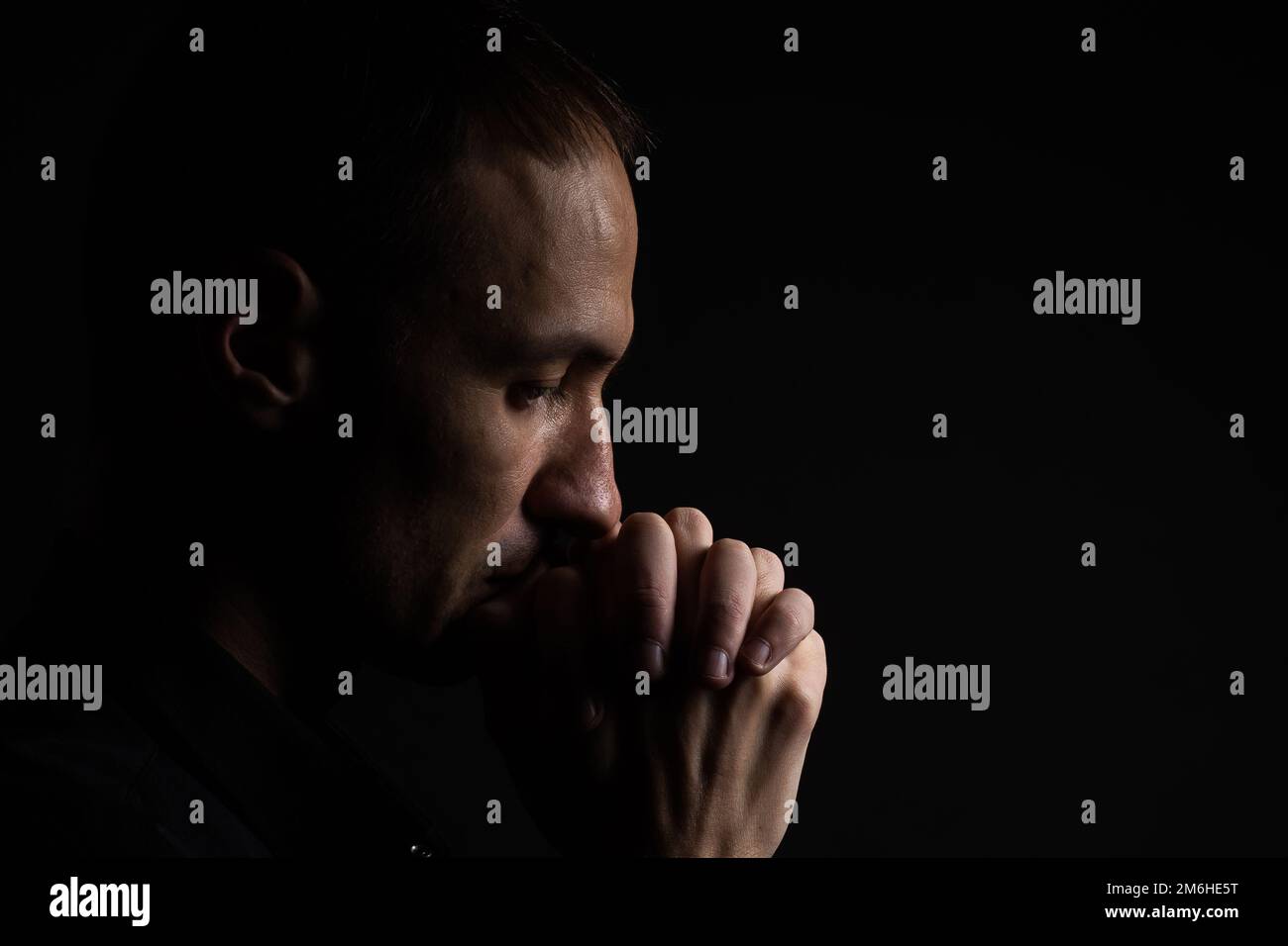 Close up of faithful mature man praying, hands folded in worship to god ...