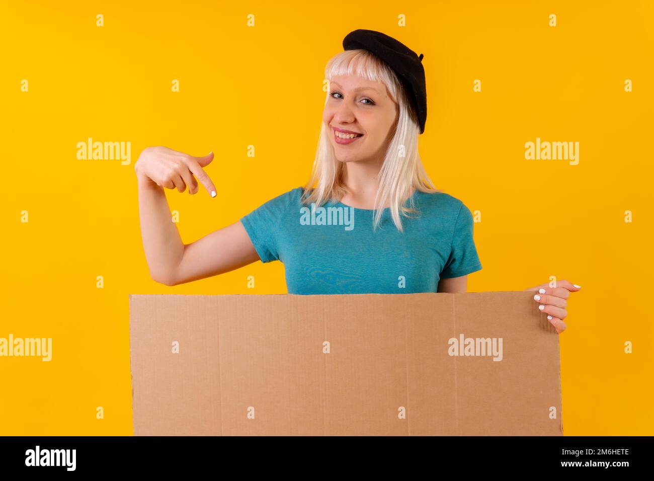 Pointing to empty cardboard advertisement poster, blonde caucasian girl ...