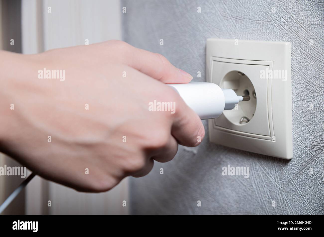 Close-up of a woman's hand inserting a white usb charger into a 220 ...