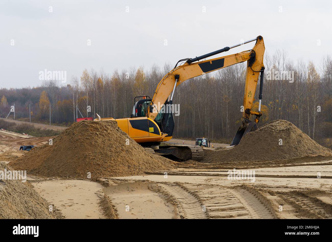 Yellow excavator is working on a sand embankment Stock Photo - Alamy