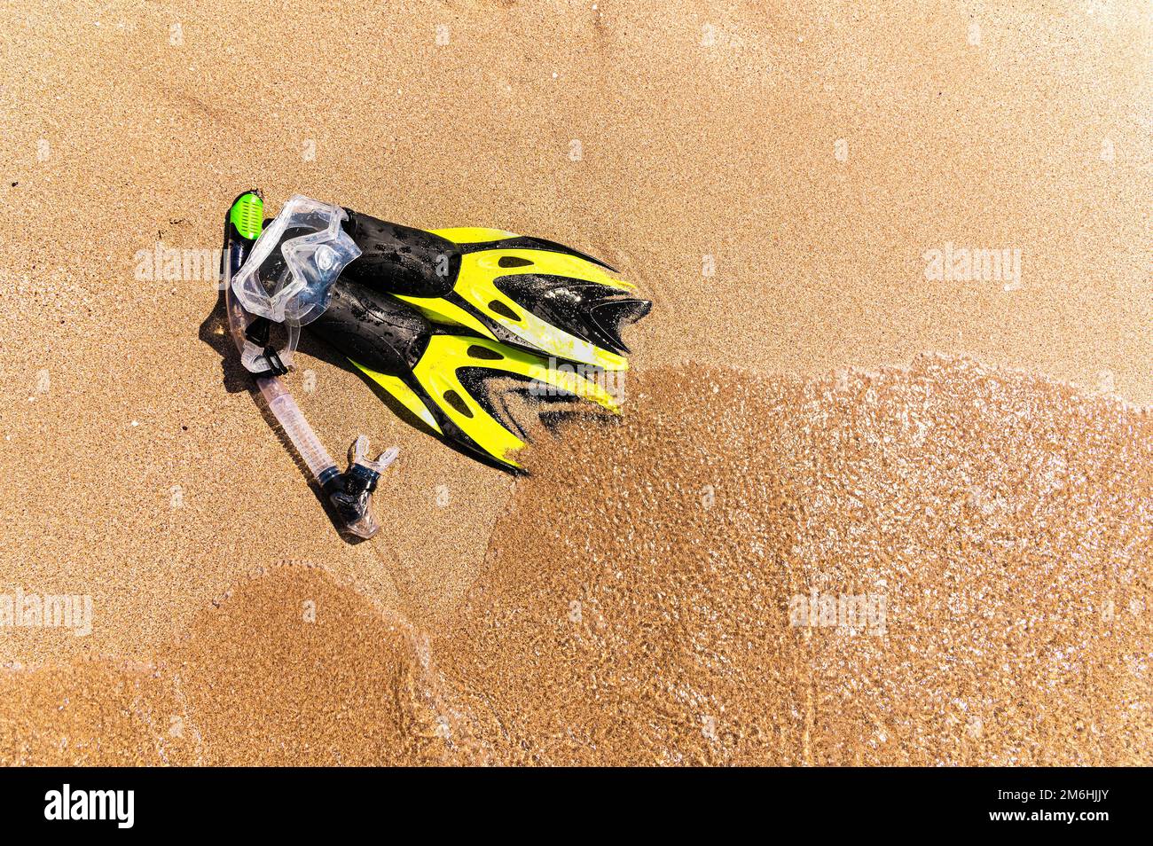 Snorkeling equipment on the sand with ocean waves splashing the water ...