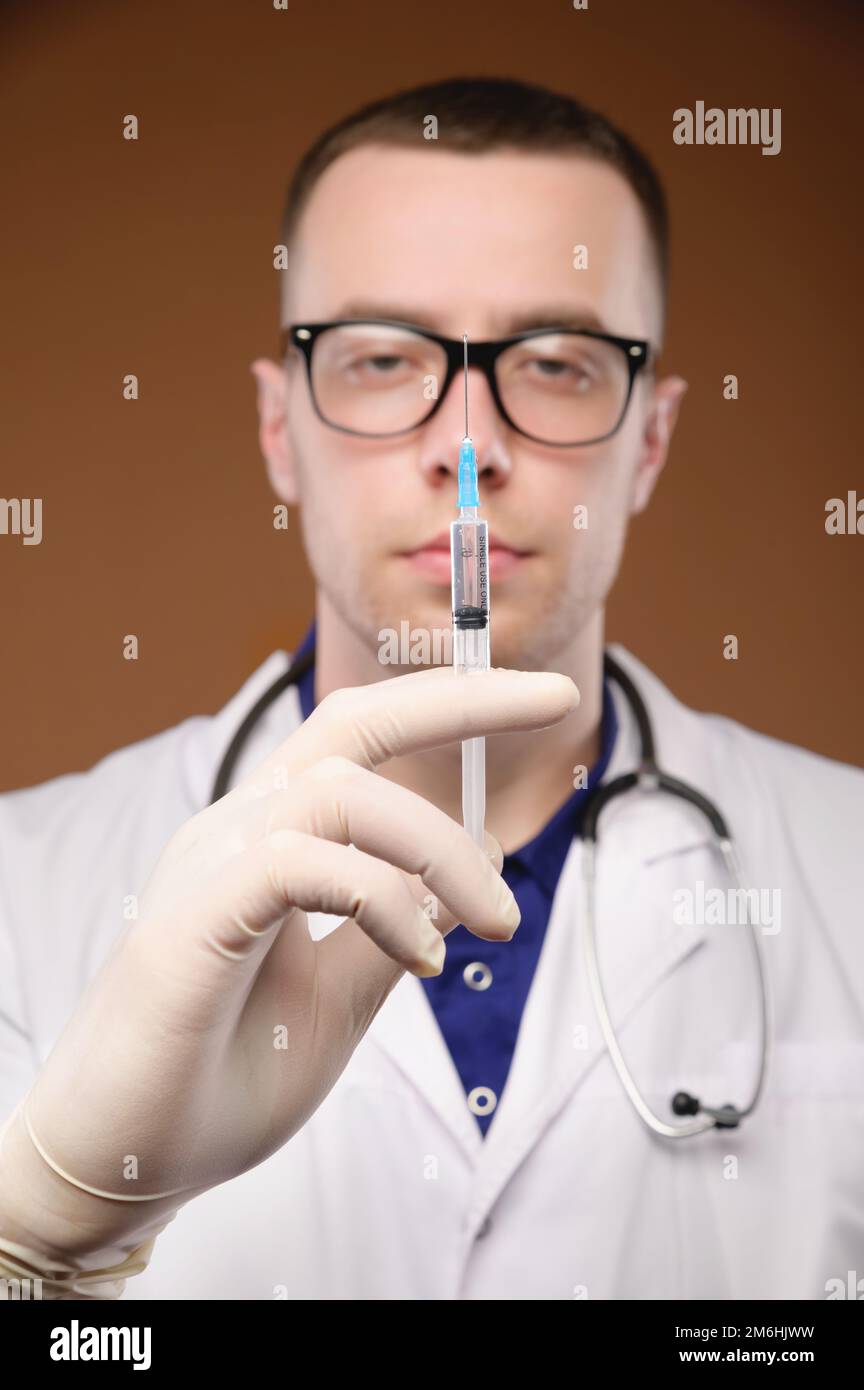 A young male doctor in glasses with a stethoscope around his neck and ...