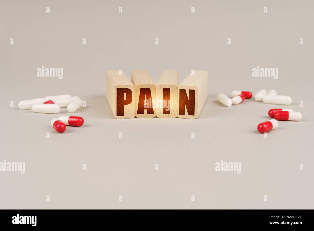 Medical concept. On a gray surface are pills and a red wooden block ...