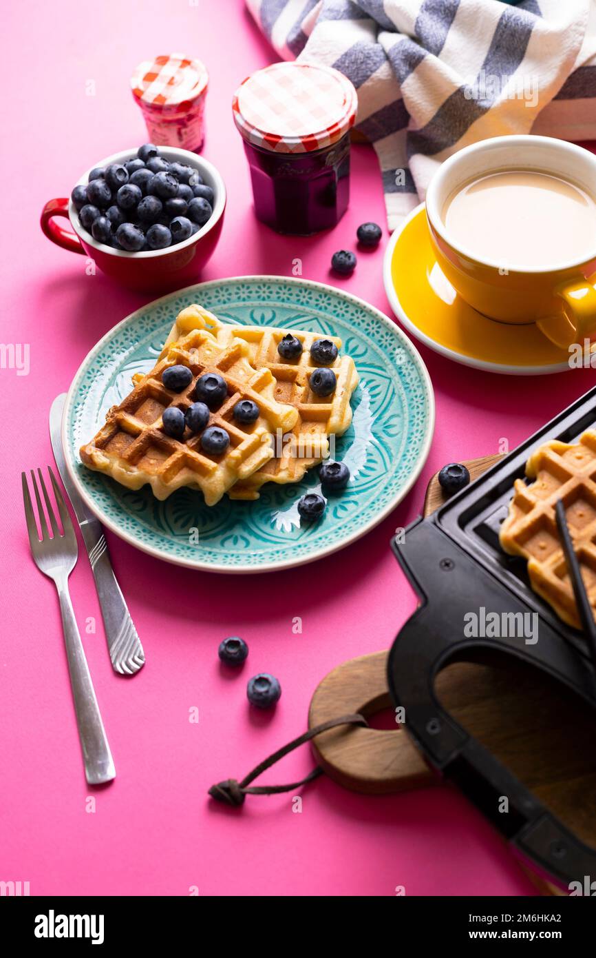 morning and bright breakfast on the pink background. belgian waffles ...