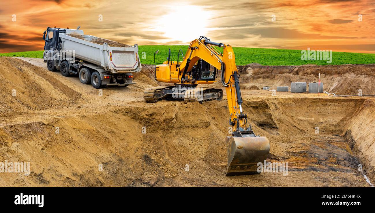 Excavator on construction site and truck at work Stock Photo - Alamy