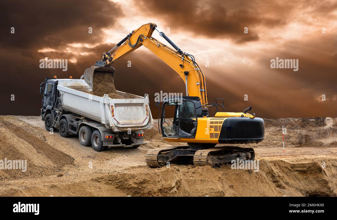 Excavator on construction site and truck at work Stock Photo - Alamy