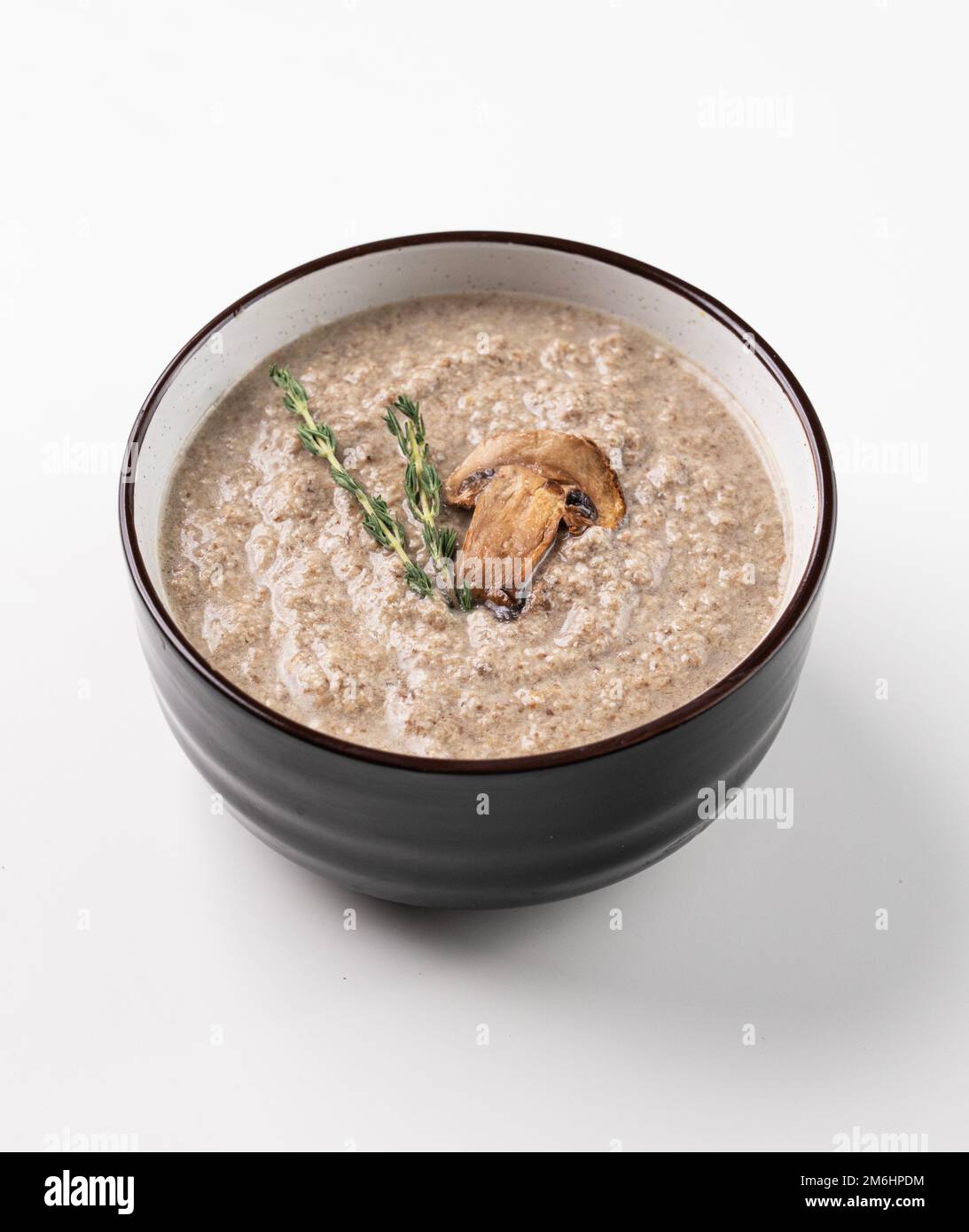 Cream soup of champignons with thyme in a ceramic bowl on a white ...