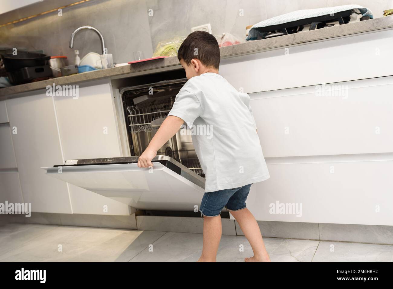 Toddler boy doing dishes in modern kitchen Stock Photo - Alamy