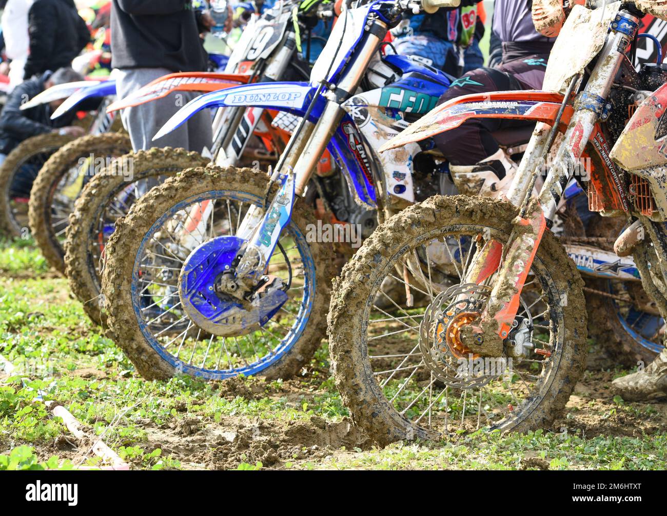 Unrecognized athletes riding a sports motorbike and muddy wheel on a ...
