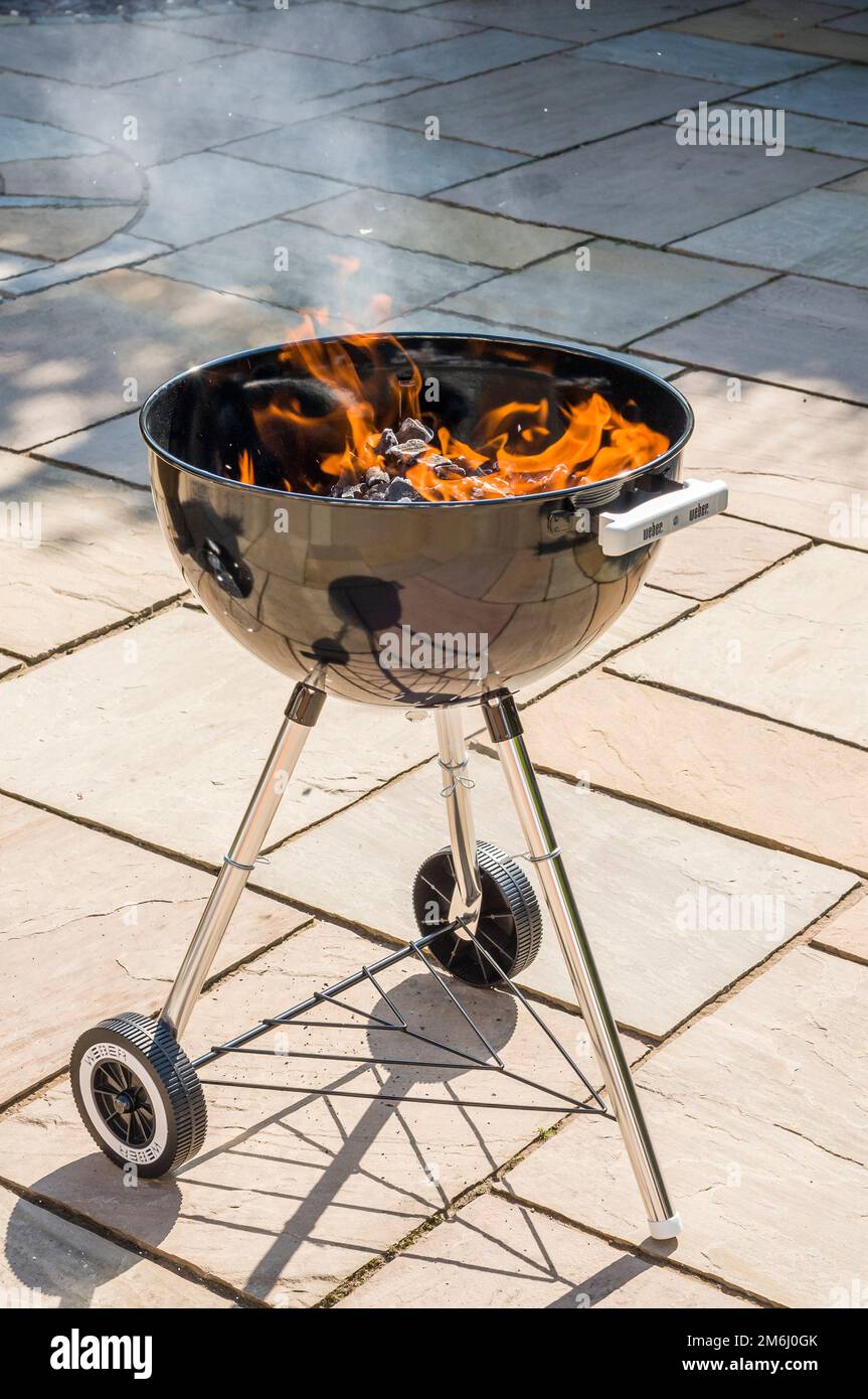 round BBQ with lit charcoal wood with flames Stock Photo - Alamy