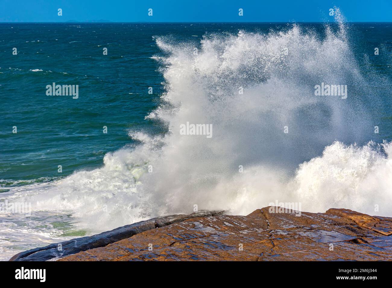 Wave breaking over rocks with water splashing with blue sky Stock Photo ...