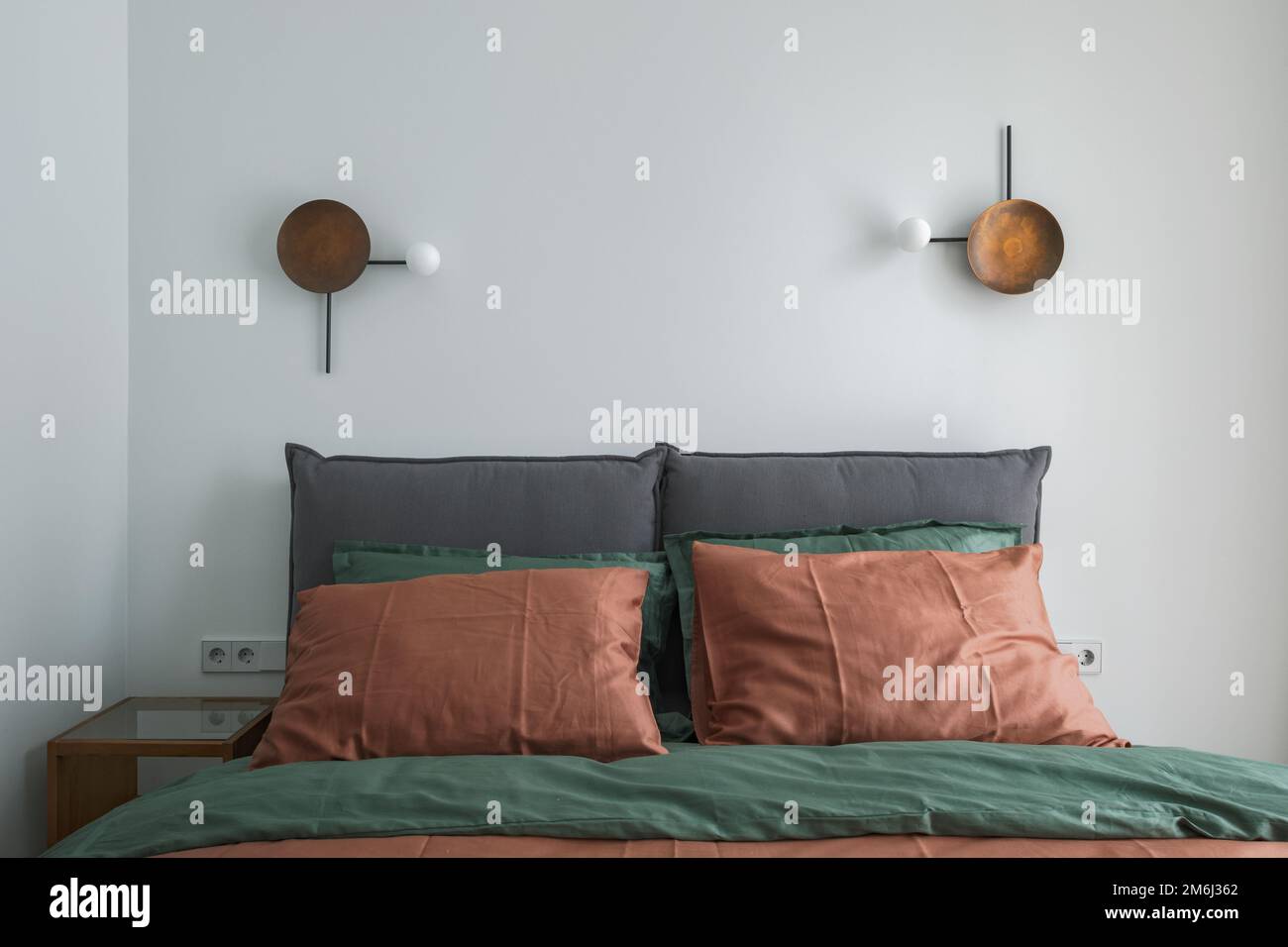 Bedroom interior with rust color linen and cushions on a bed, grey ...