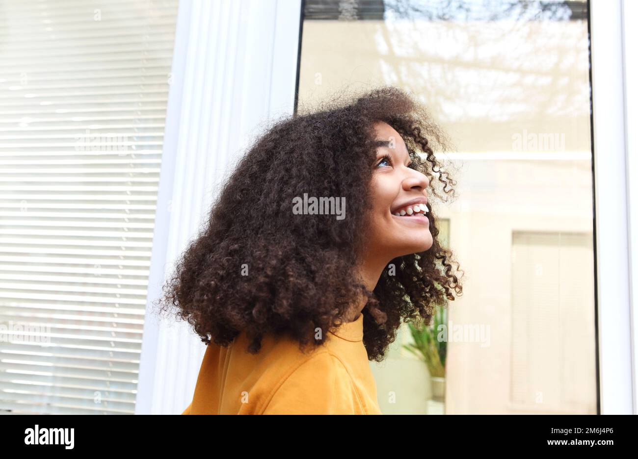 Happy positive young african american lady looking up and smiling while ...