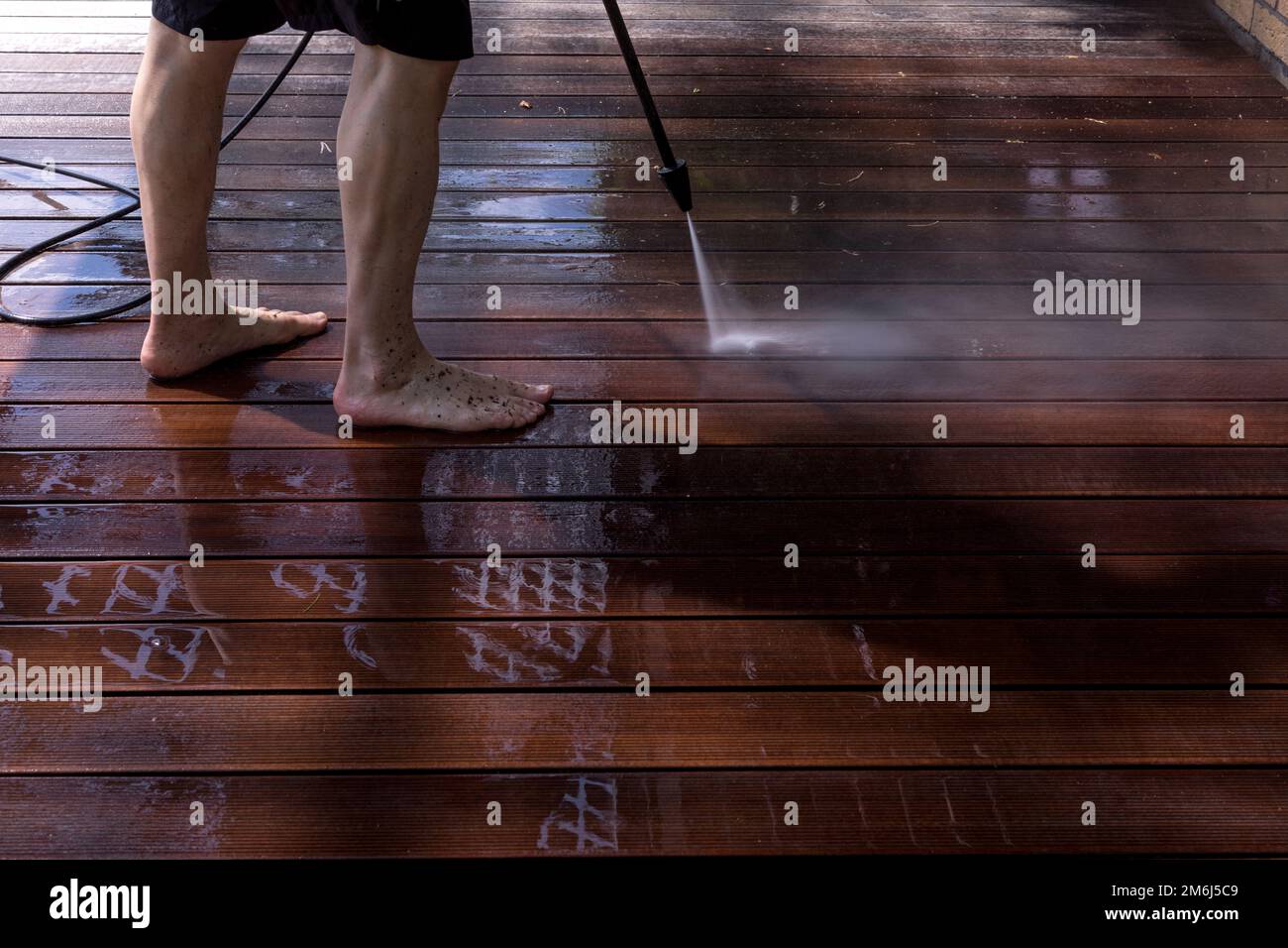 Power surface washing. Man cleaning terrace with a power washer. High ...