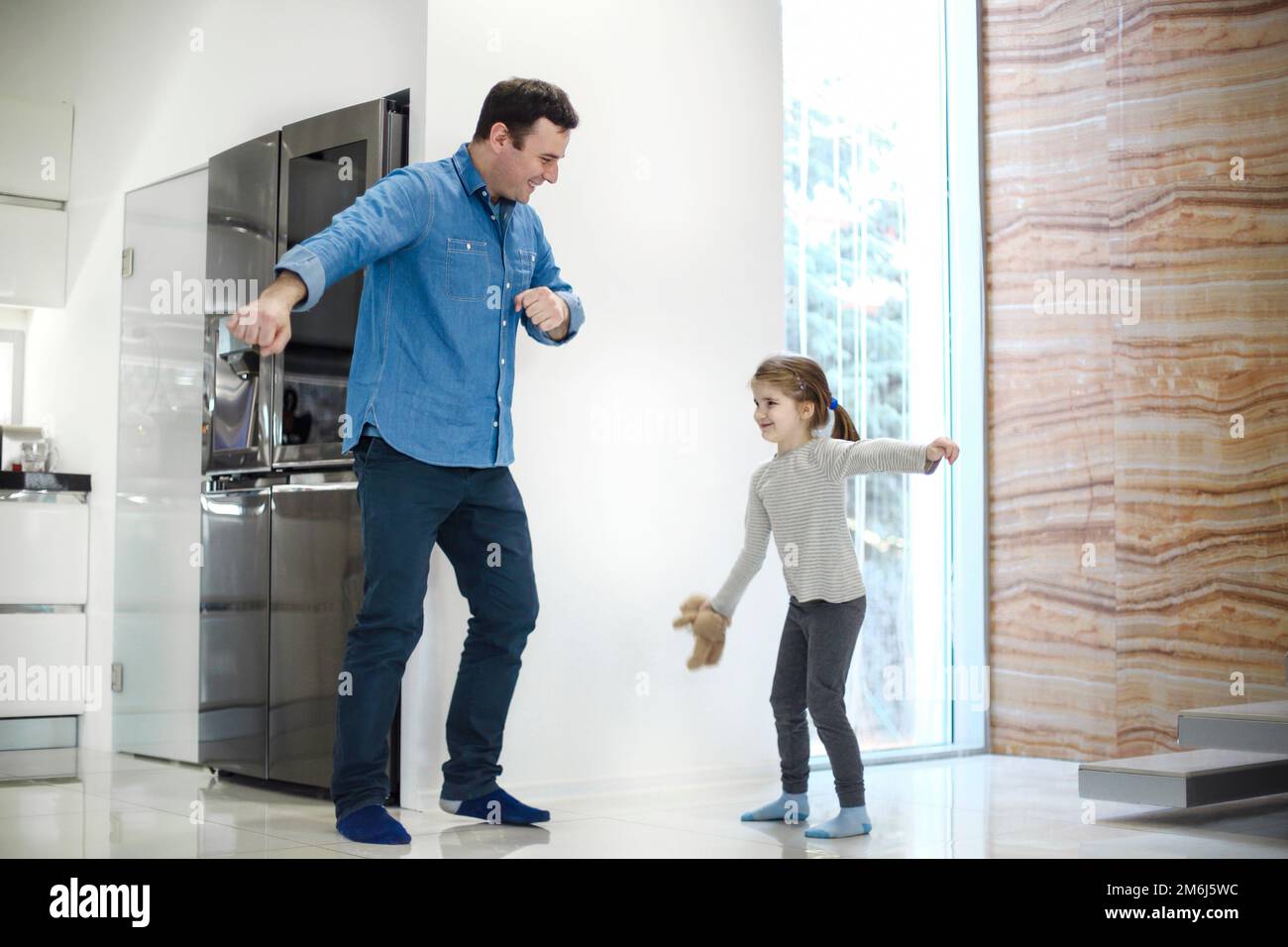 Father and daughter dancing in corridor by window at home Stock Photo ...