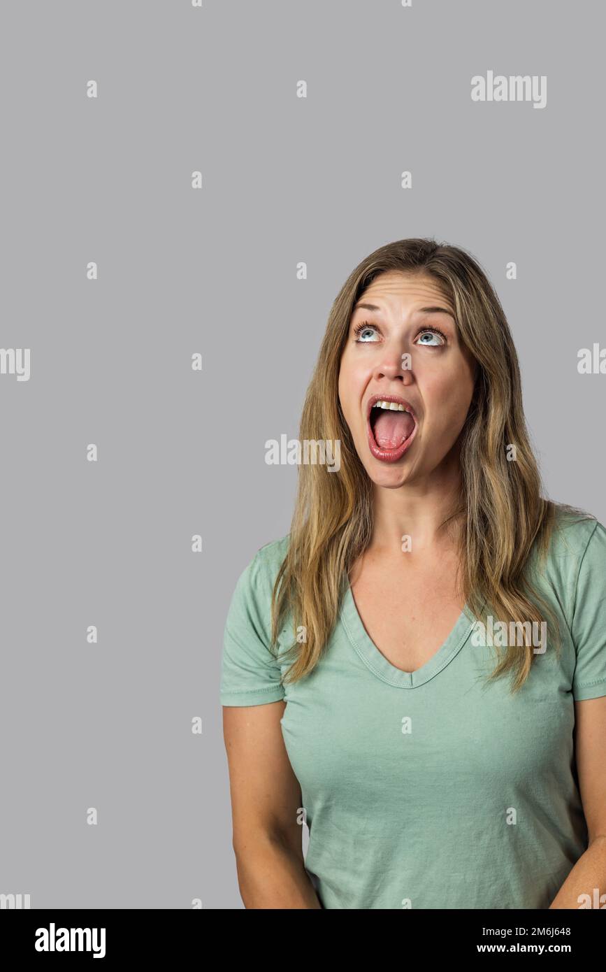 An attractive brunette woman in her forties wearing at shirt looking up with her mouth open in ...