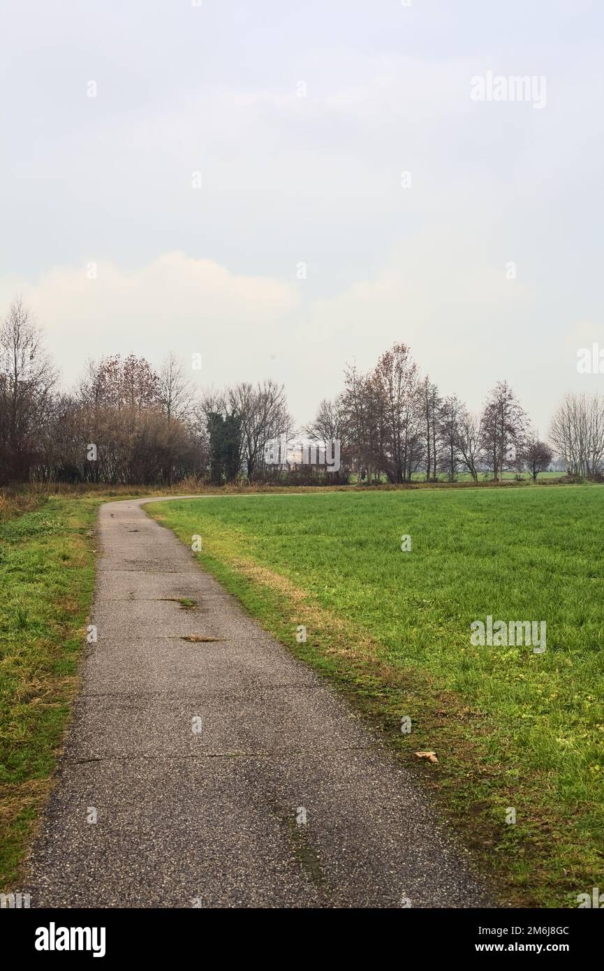 Paved trail in the fields on a cloudy day in the italian countryside ...