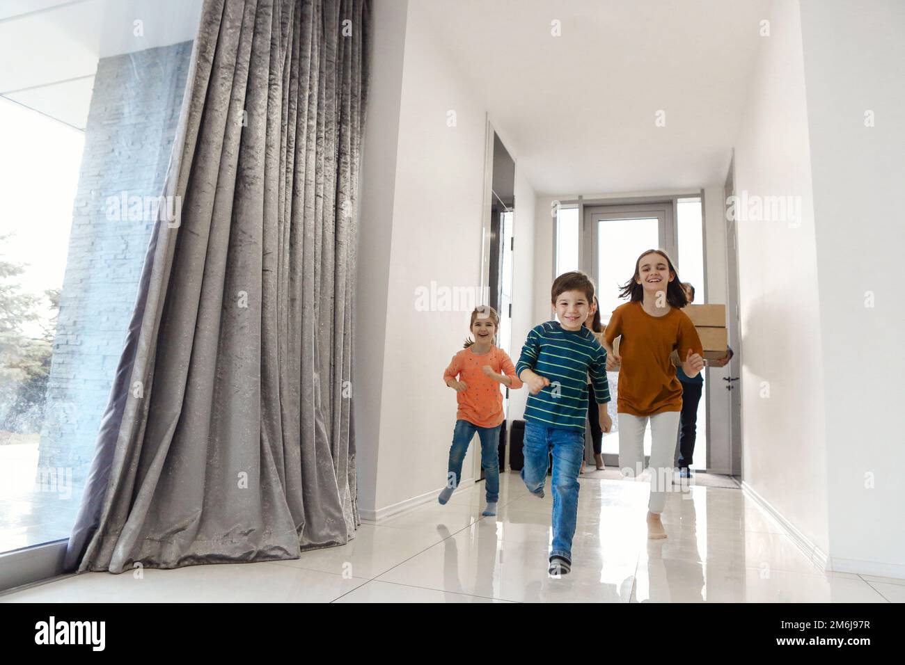 Happy family running in hall. Funny kids jumping with carton box ...