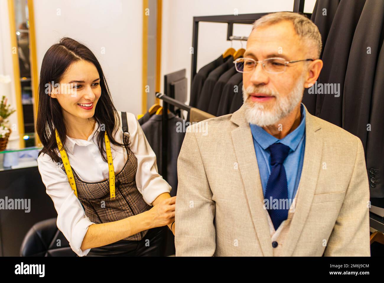 a professional tailor woman trying on a tailor-made suit for an elderly man Stock Photo - Alamy