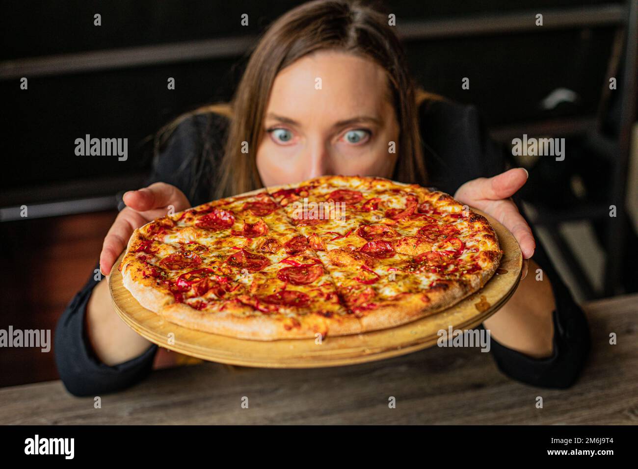 Hungry woman hold in hand wooden tray with fresh appetizing pizza and ...