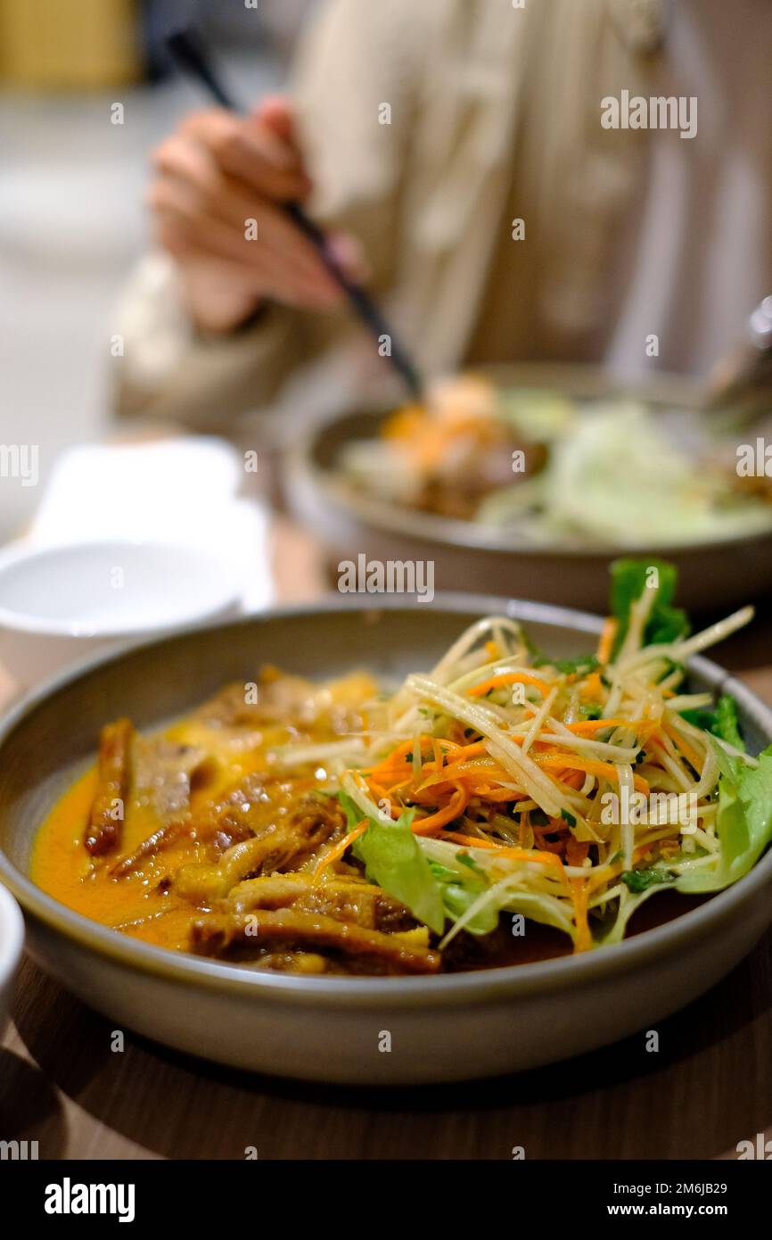 A vertical closeup shot of a plate full of Vietnamese food at a ...