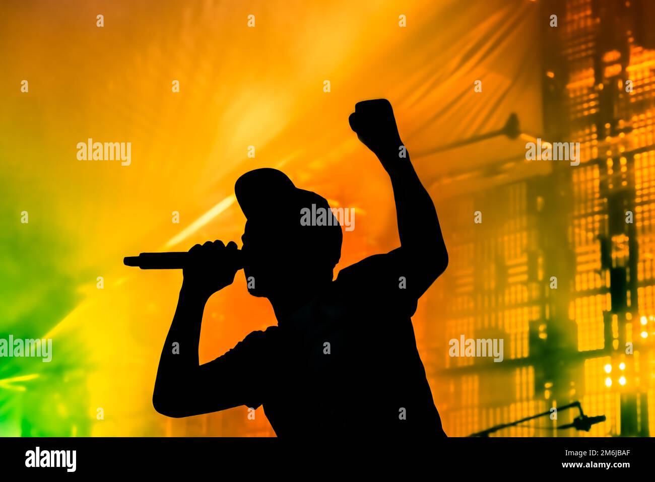 Silhouette of a male singer performing in front of a musical equipment ...
