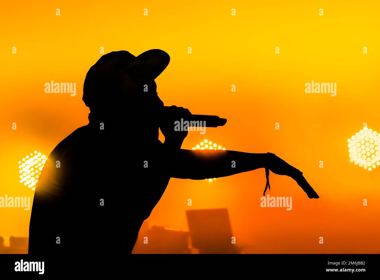 Silhouette of a male singer performing in front of a musical equipment ...