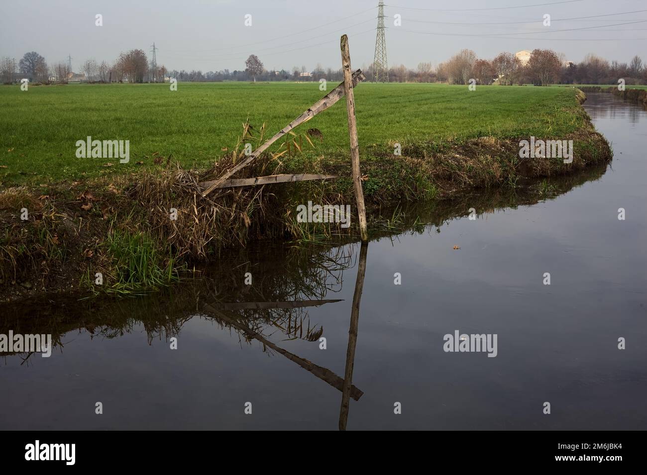 Stream of water in the countryside and a mooring pole by the shore with ...
