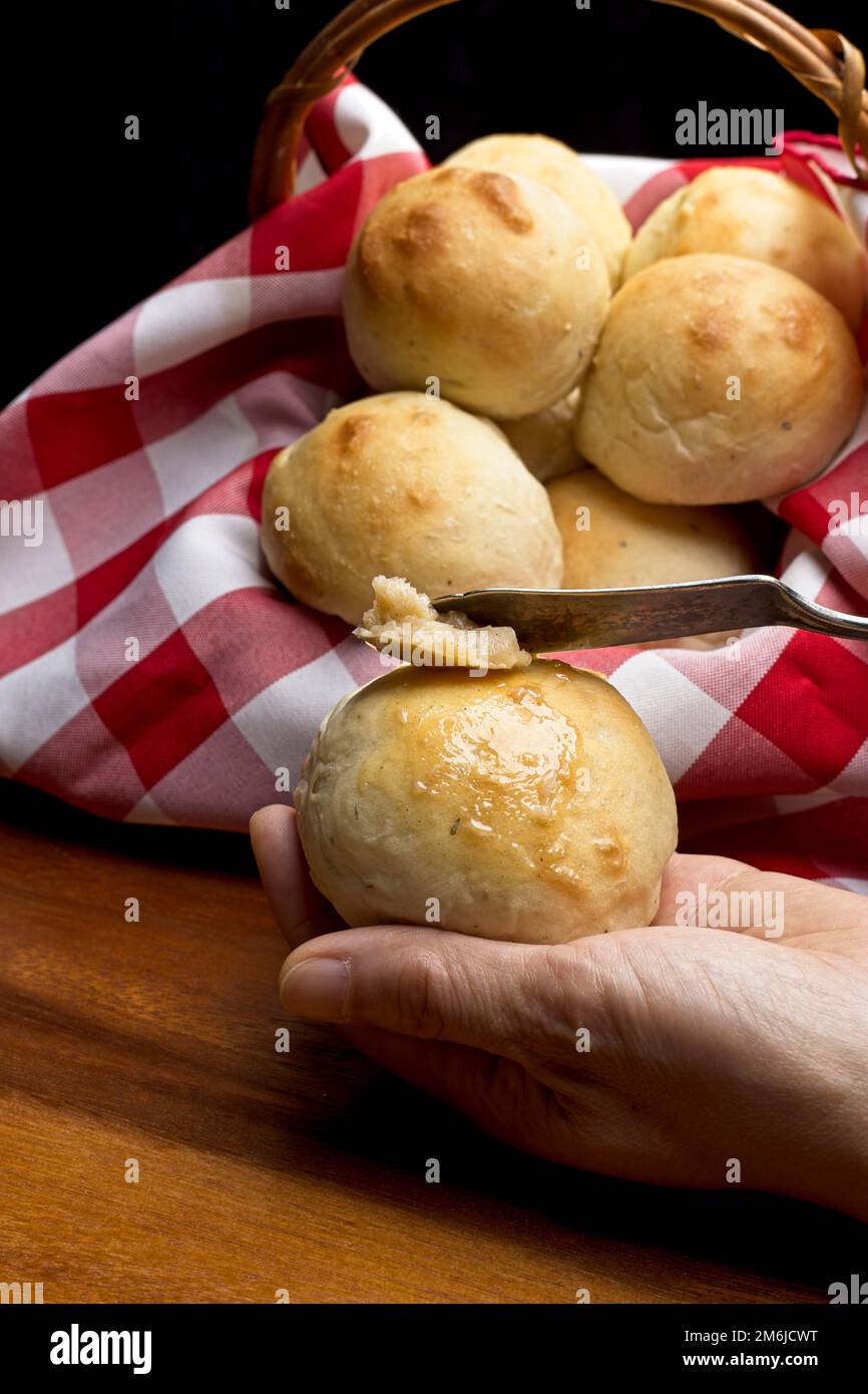 A close up photo of hands holding a roll and spreading butter over the ...