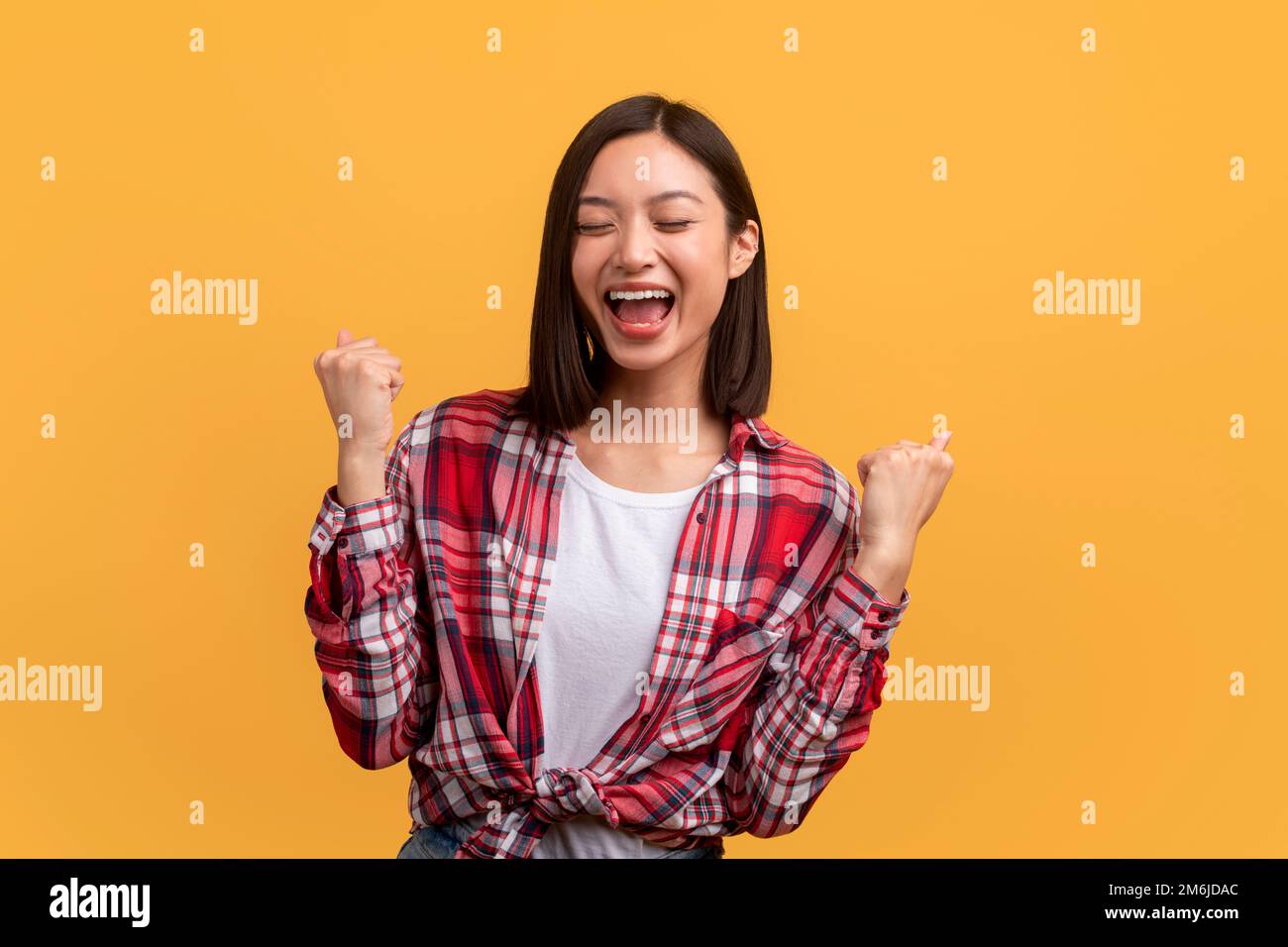 Overjoyed asian lady gesturing yes and shaking fists, screaming with ...