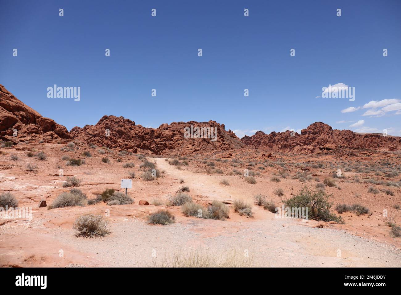 Hills of bright red Aztec sandstone behind the harsh, desert landscape ...
