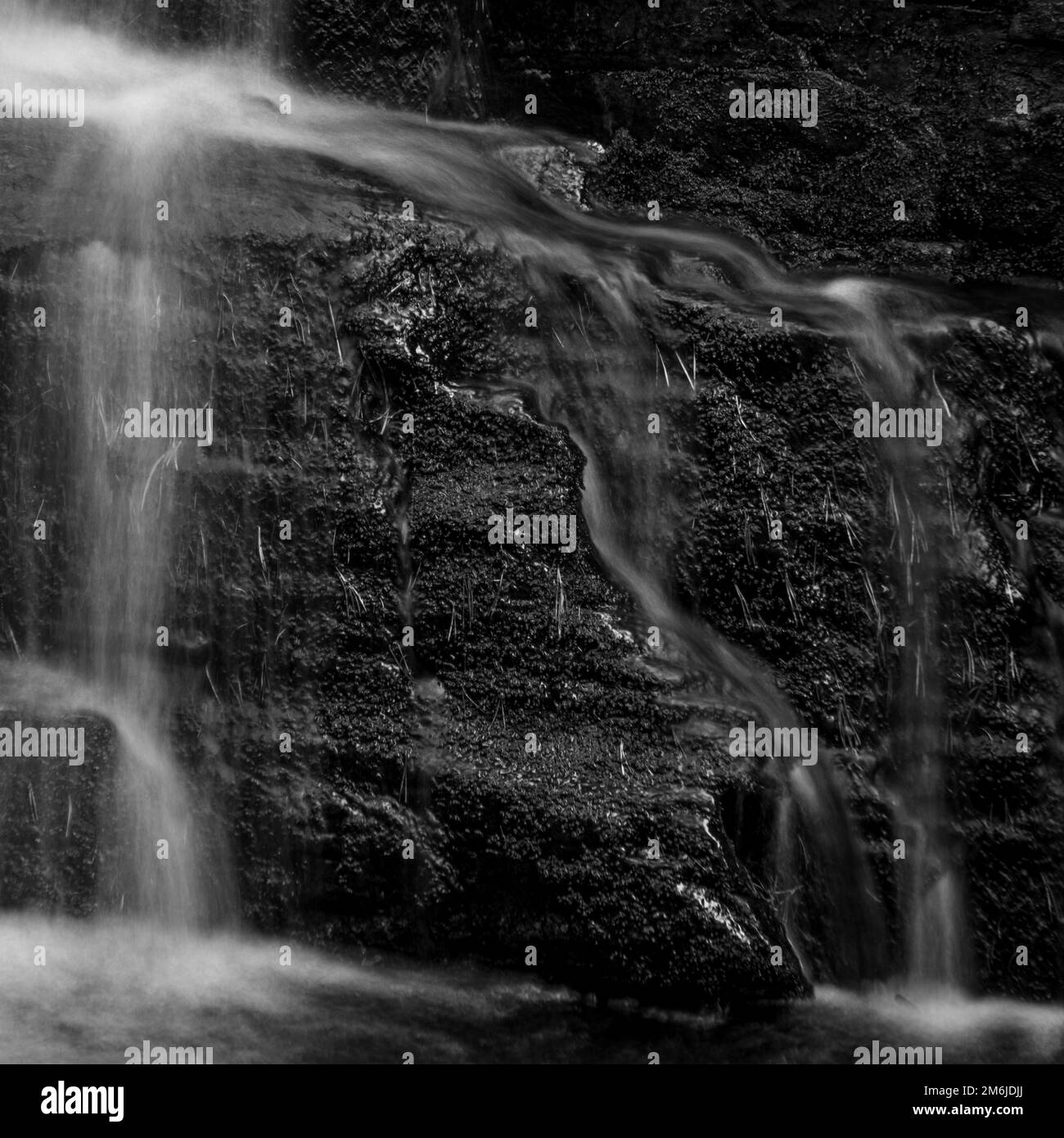 A beautiful grayscale of a waterfall over the rocky cliff Stock Photo ...