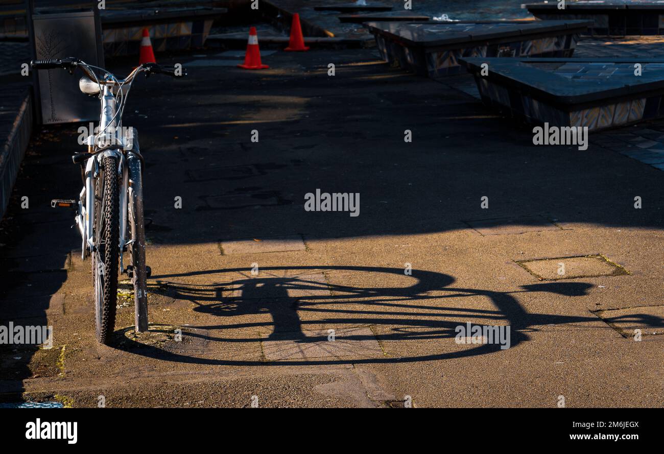A stray bike casting a shadow on the sidewalk Stock Photo - Alamy