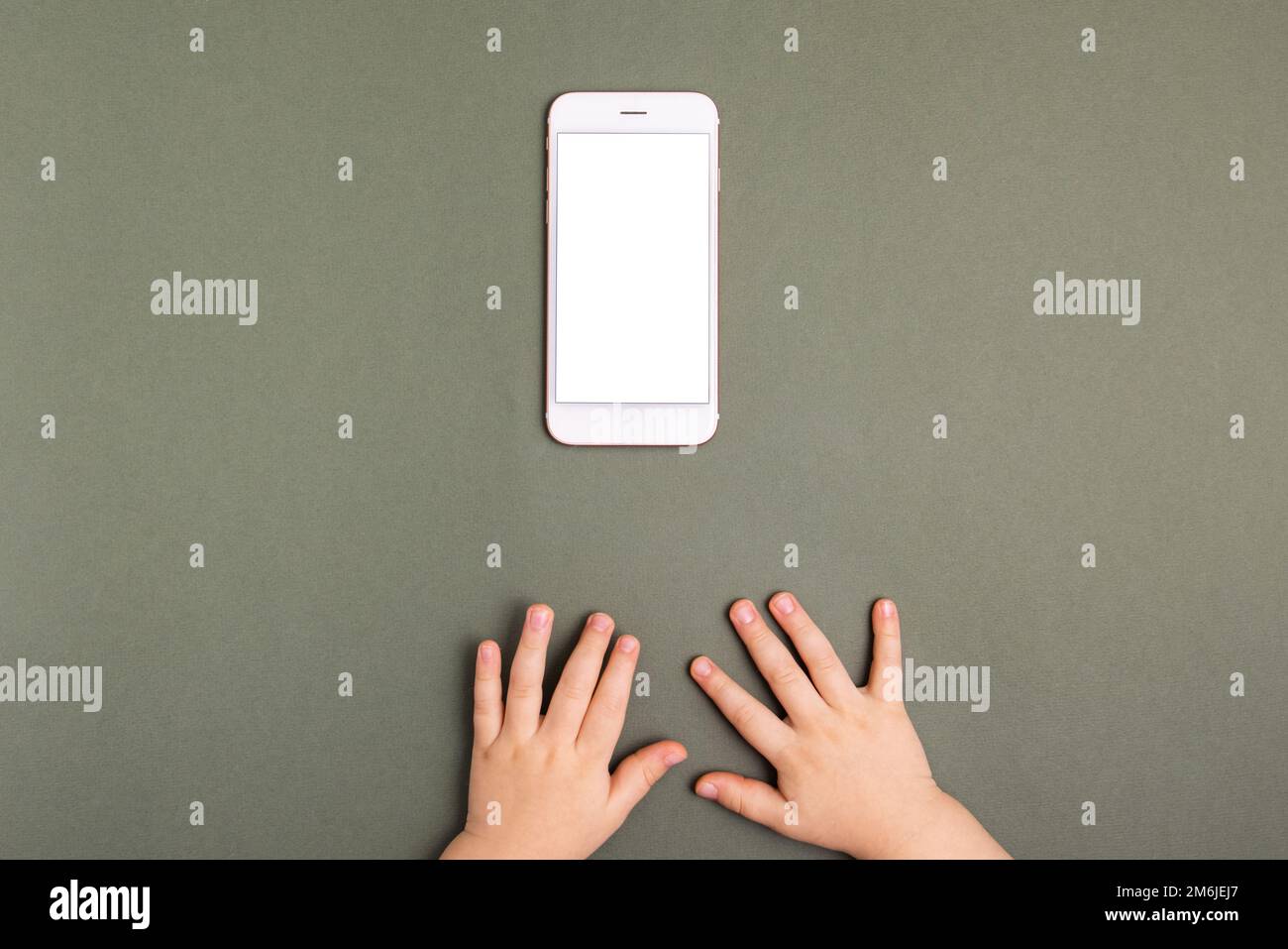 Flat lay view hand of child and smart phone over green background ...