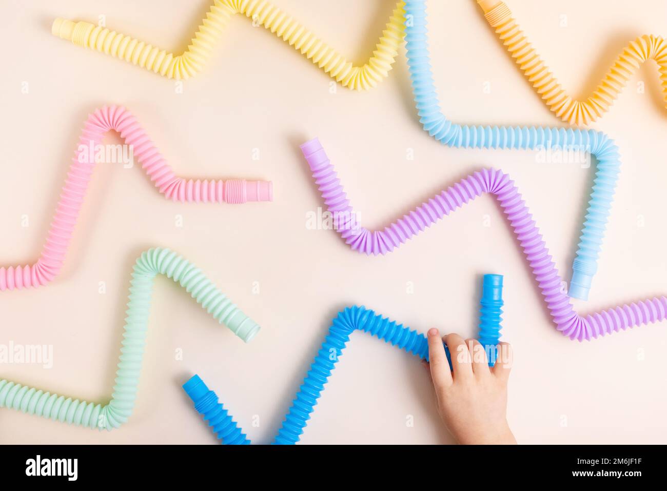 Trendy kids toys pastel colorful pop-tube in baby toddler hands on ...