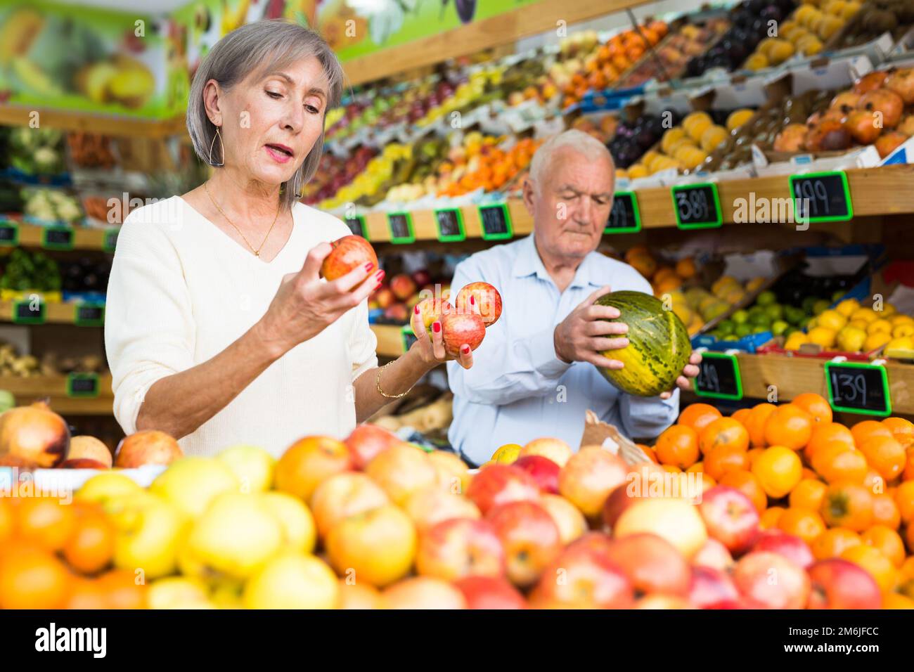 Mature woman and man selecting fruits in greengrocer Stock Photo - Alamy