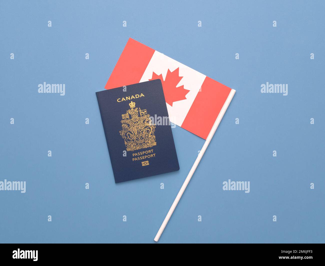 A Canadian passport on a Canadian Flag against a solid light blue ...