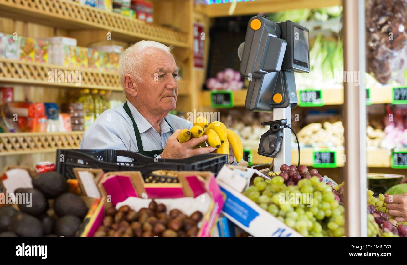 Portrait of a positive male salesperson at the checkout counter at ...