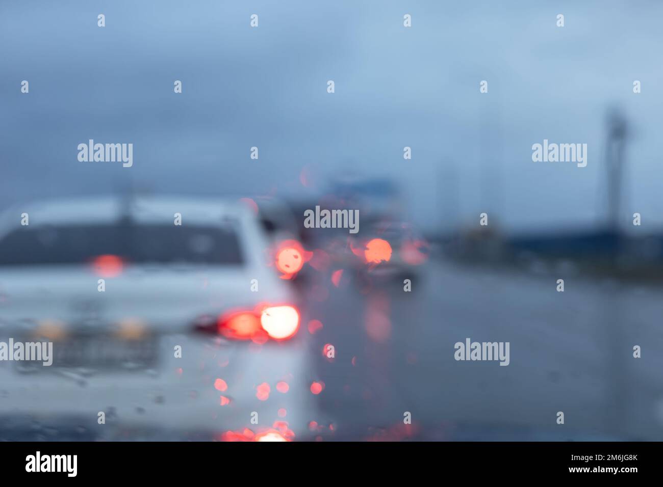 Blurred view through the wet windshield of cars driving down the road ...