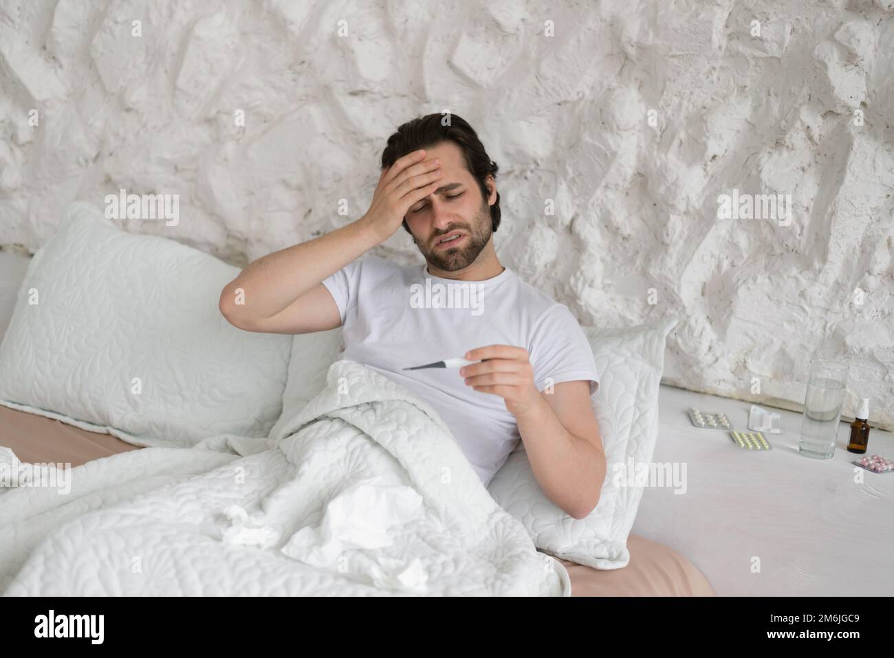 Unhappy sad young caucasian man suffers from headache and fever, look ...